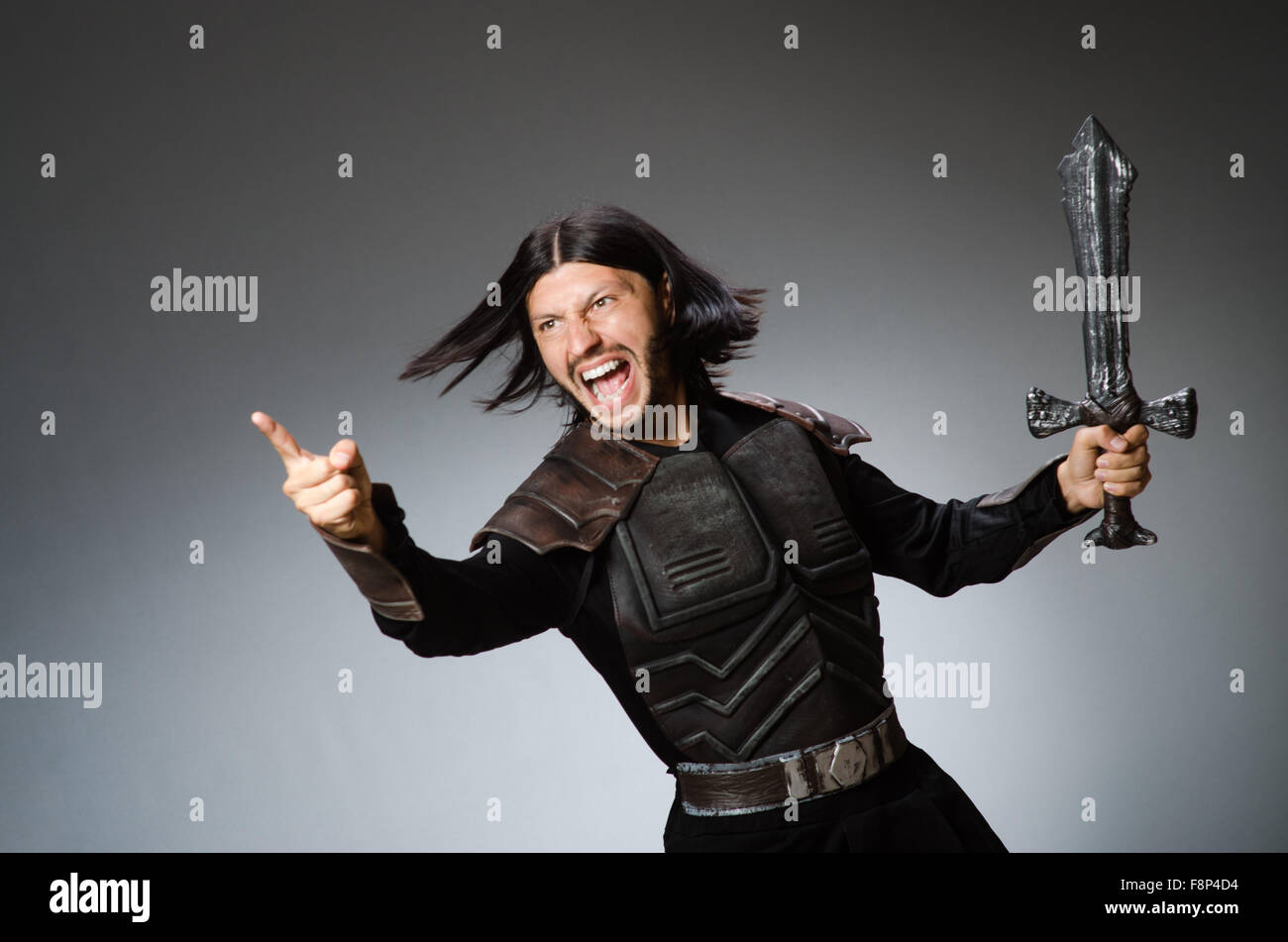 Angry knight with sword against dark background Stock Photo - Alamy