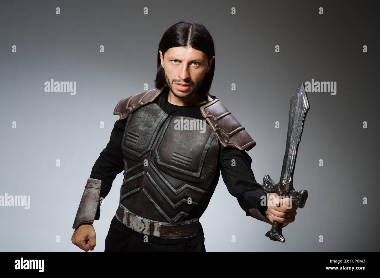 Angry knight with sword against dark background Stock Photo - Alamy