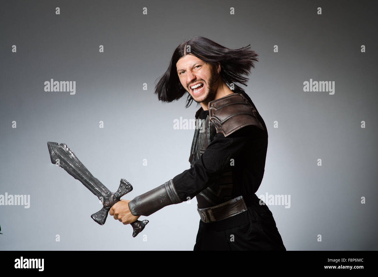 Angry knight with sword against dark background Stock Photo - Alamy