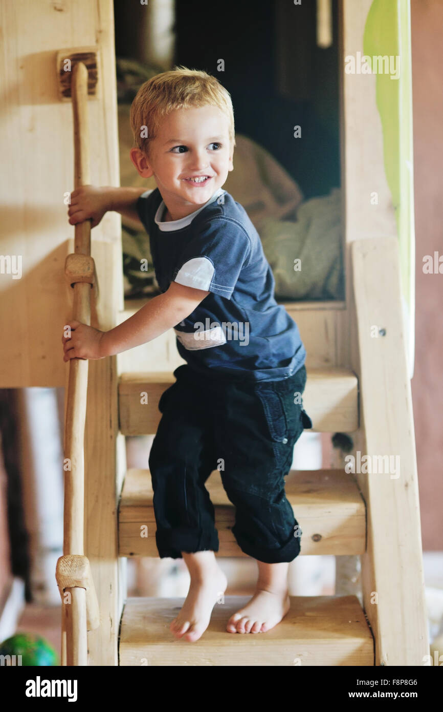 beautiful young child making first steps and have fun in play ground ...