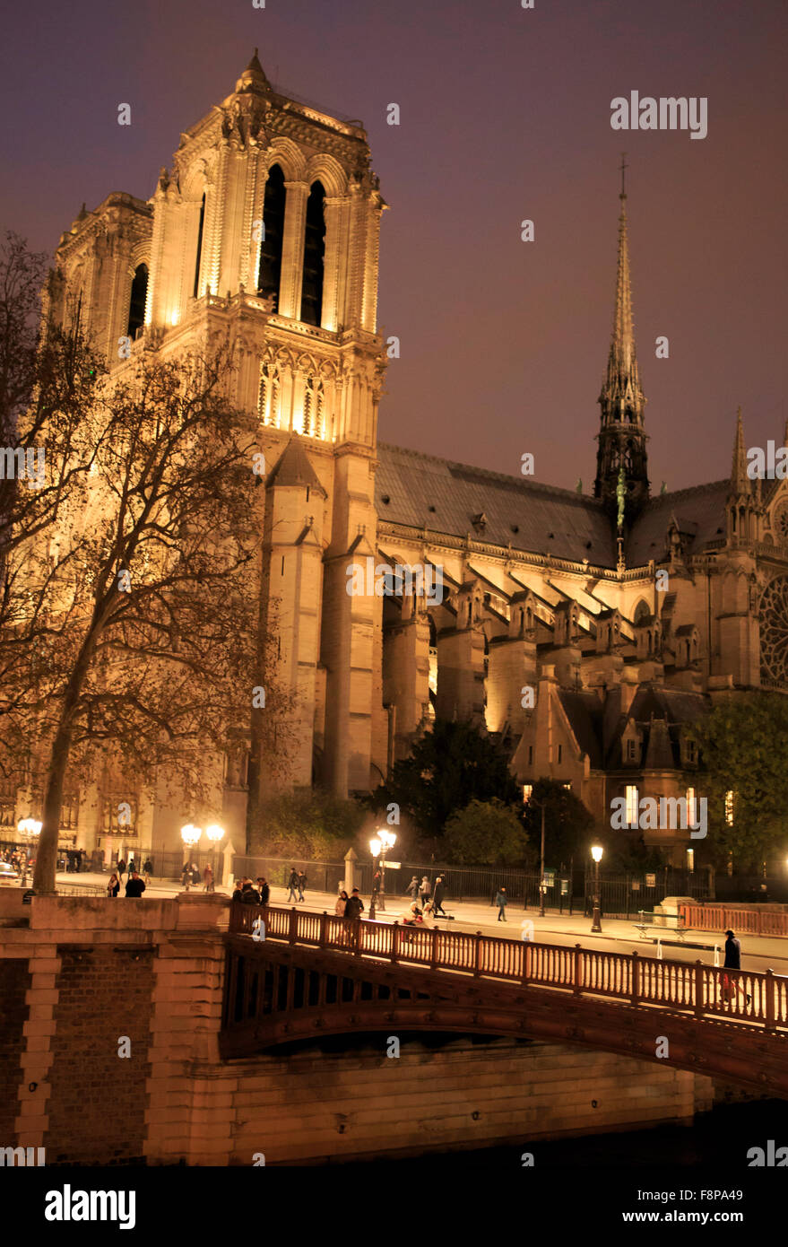 Tourists cross a bridge over a canal towards the Notre Dame Cathedral ...