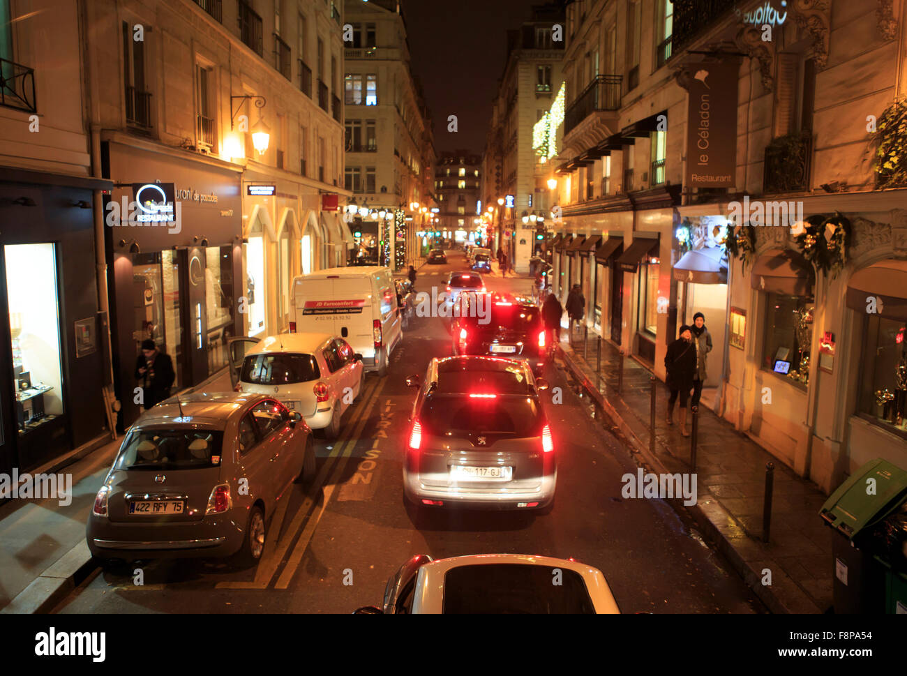 Cars lined up along a narrow Parisian street at night. Paris, France ...