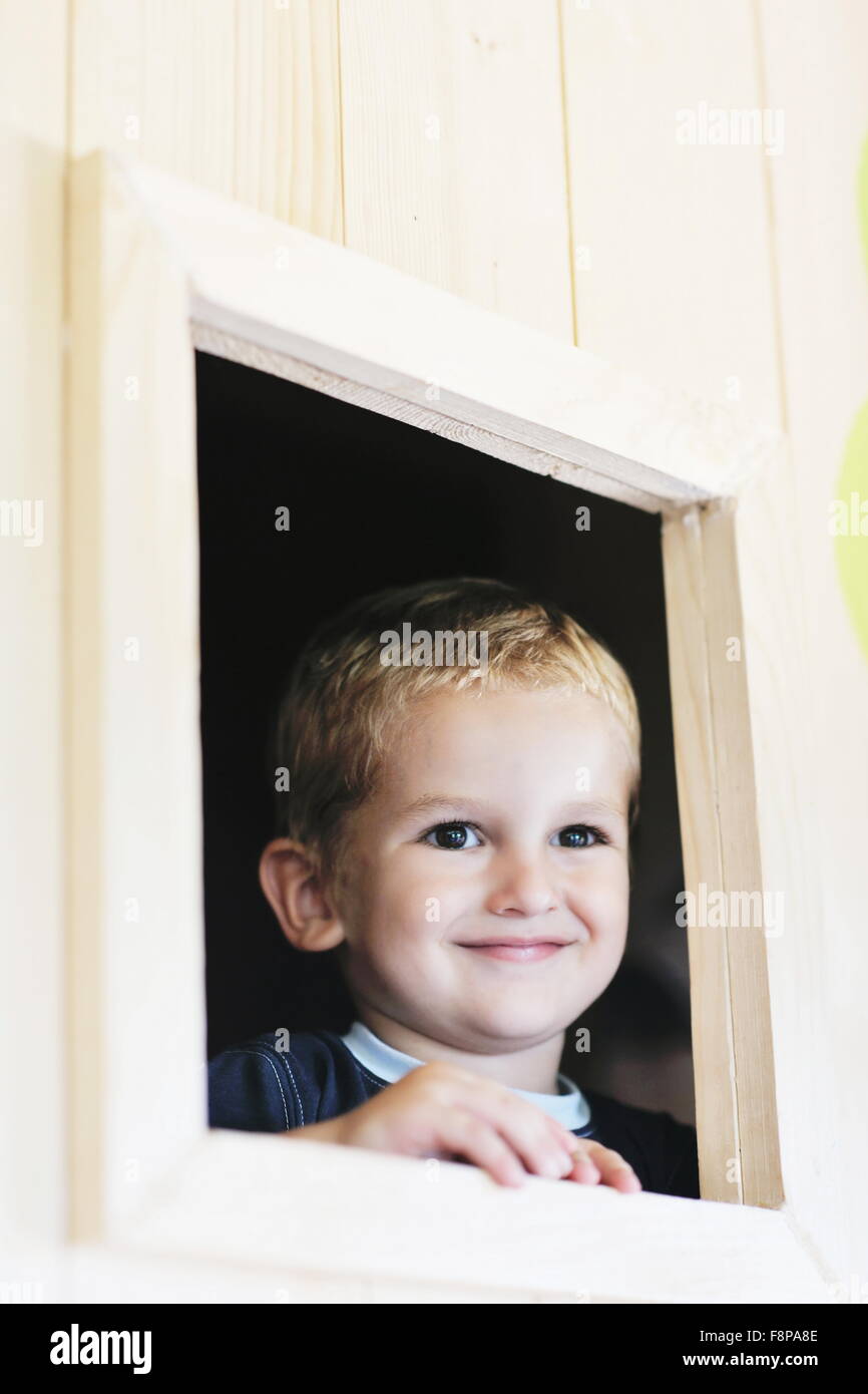 happy cute child in a wooden window at playground Stock Photo - Alamy