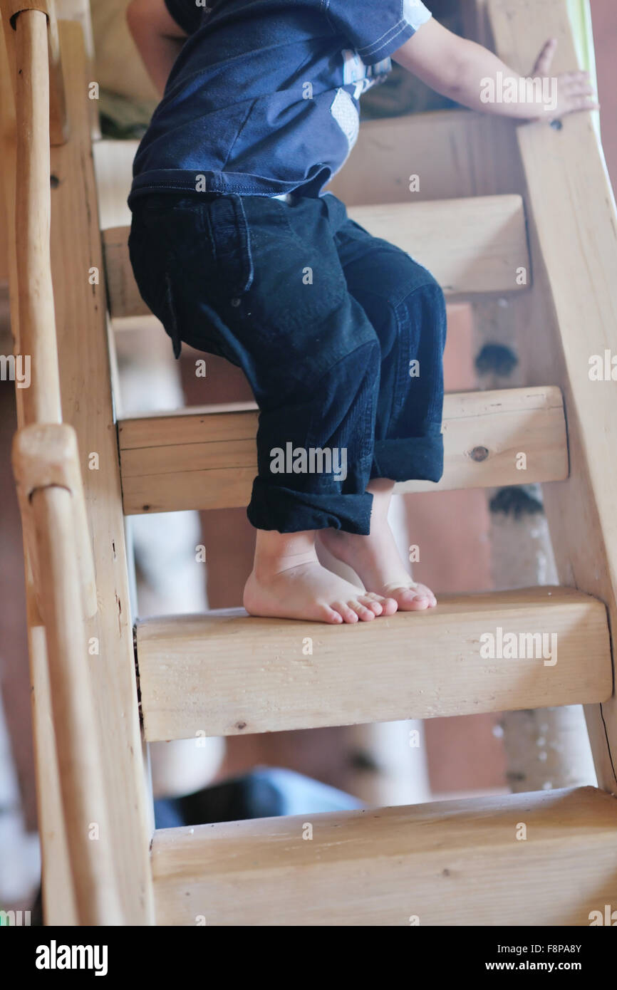beautiful young child making first steps and have fun in play ground ...