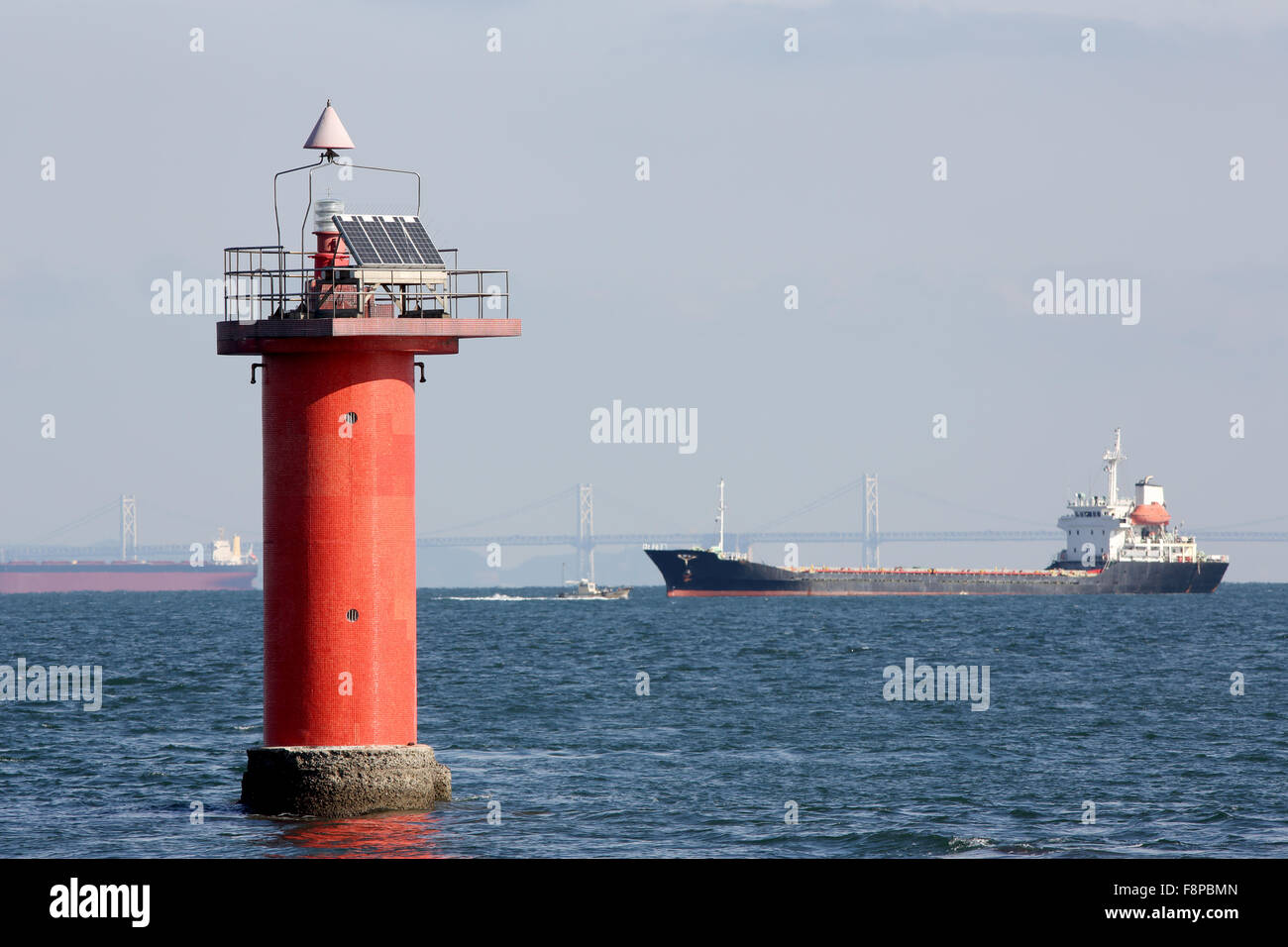 lighthouse with cargo ship in the sea Stock Photo - Alamy