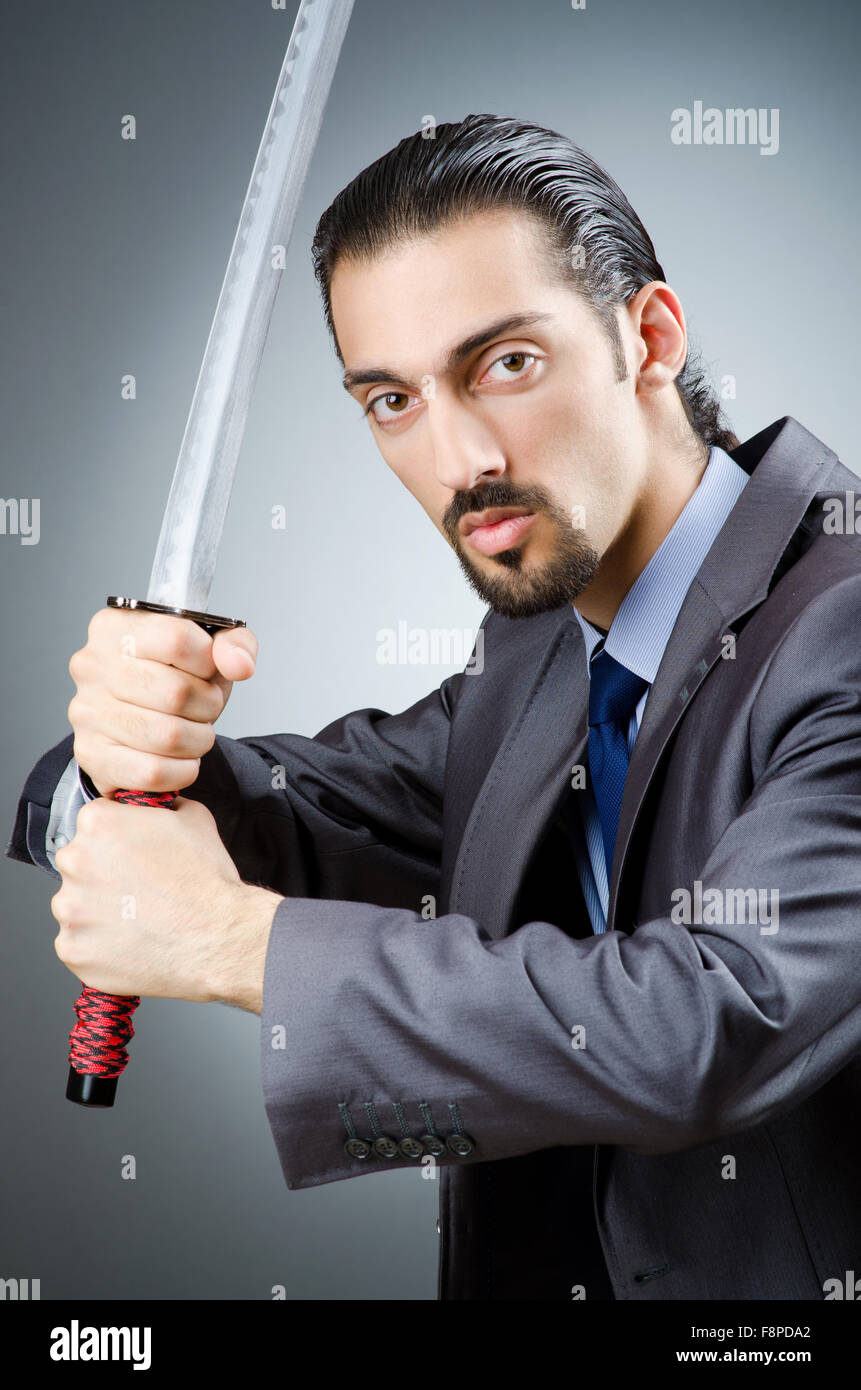 Angry businessman with sword in dark room Stock Photo - Alamy