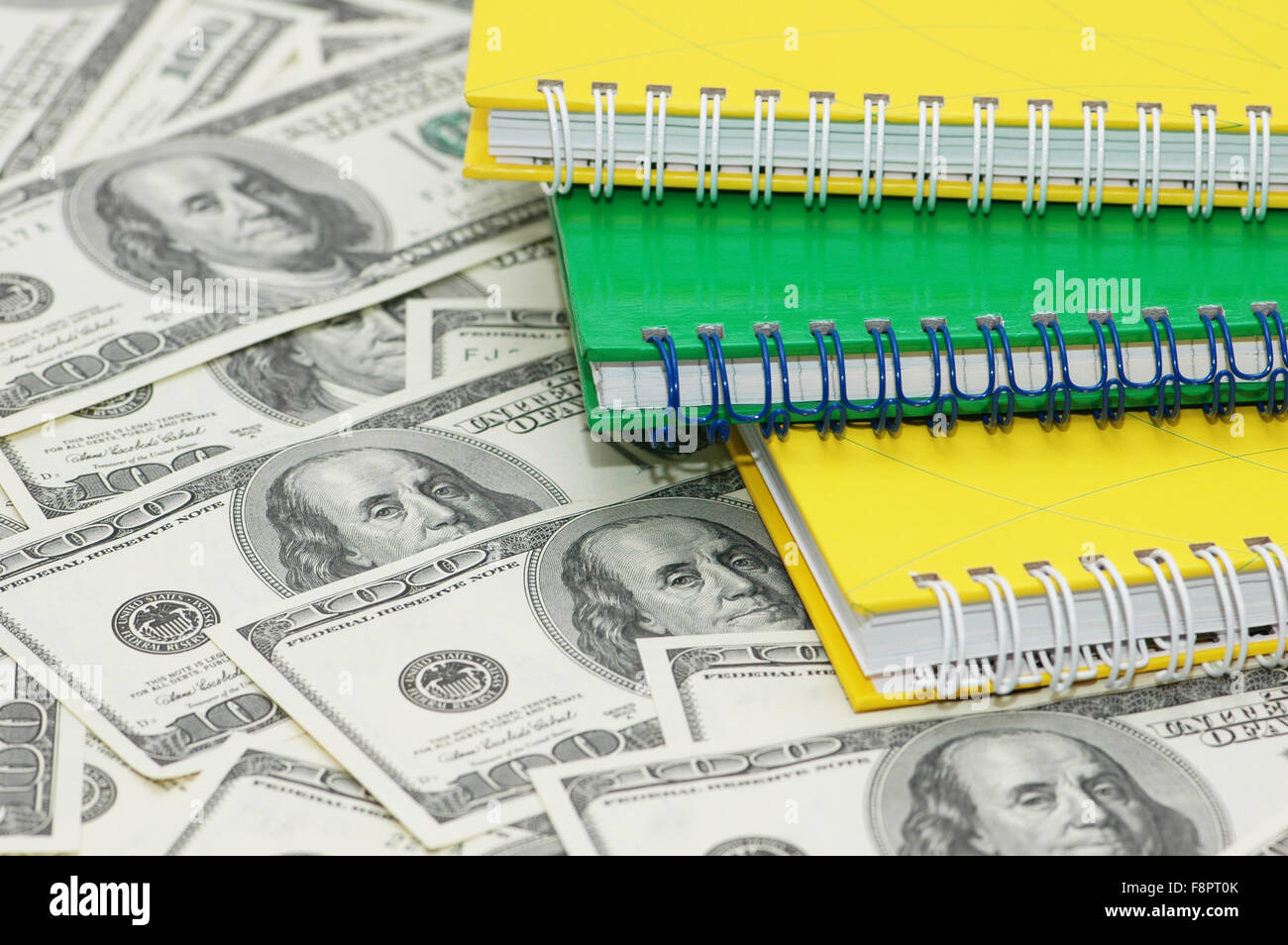 Three spiral notebooks and us dollar background Stock Photo - Alamy