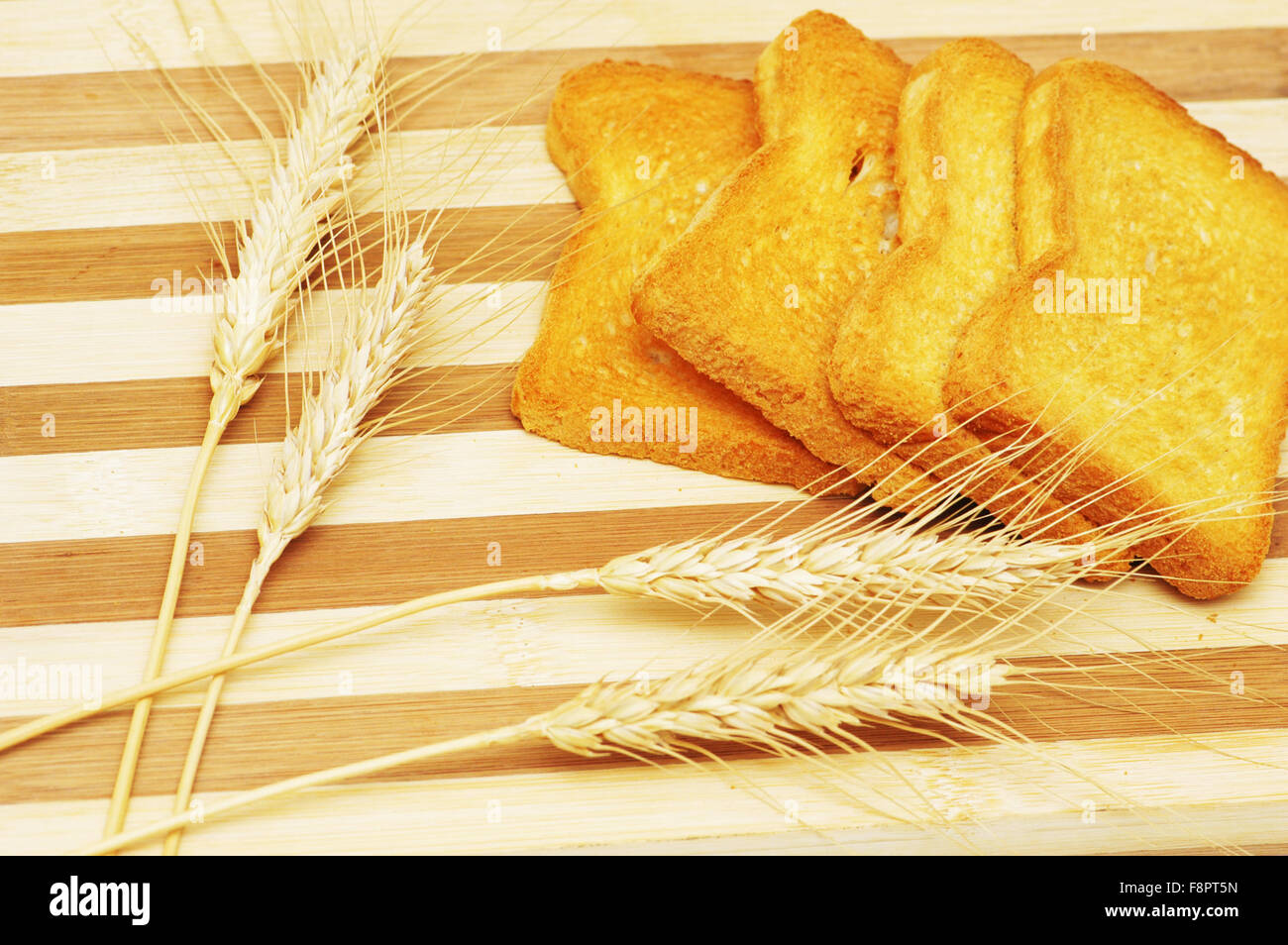 Four toast pieces and wheat ears on wooden board Stock Photo - Alamy