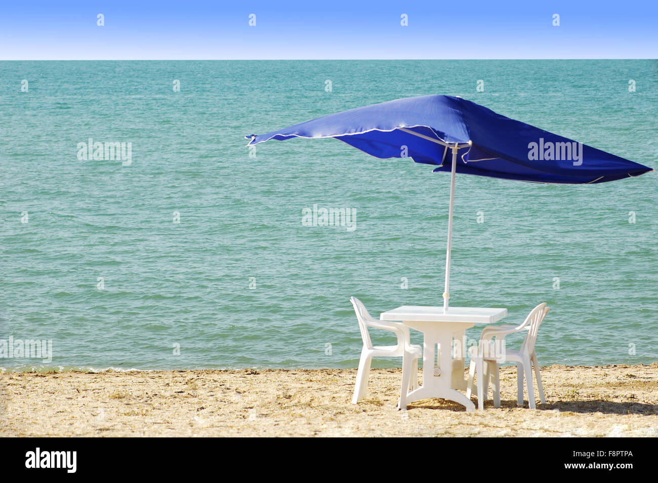 Table, chairs and parasol on the beach Stock Photo - Alamy