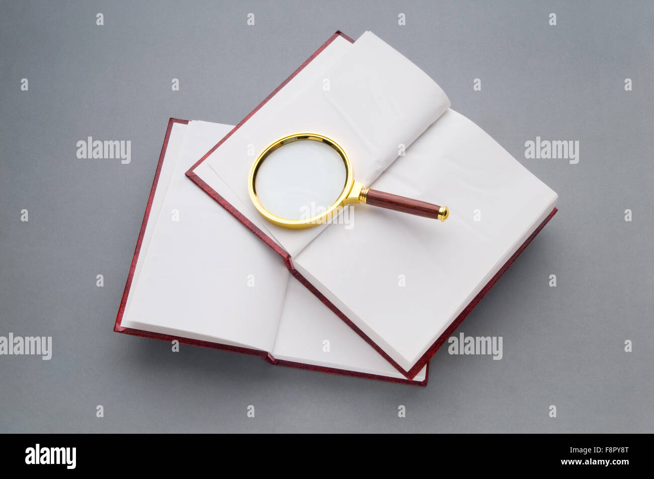 Magnifying glass over the stack of books Stock Photo - Alamy