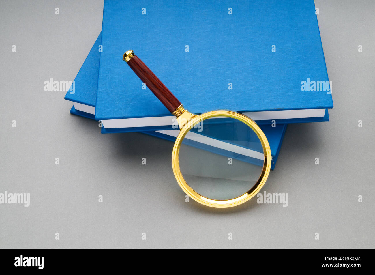 Magnifying glass over the stack of books Stock Photo - Alamy