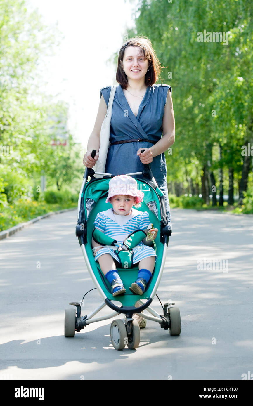 Young woman with stroller walking at summer park Stock Photo - Alamy