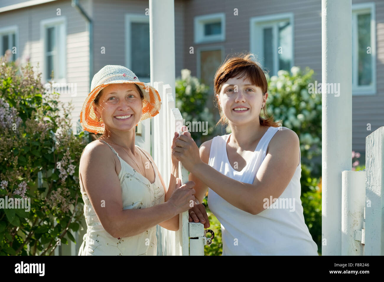 Two happy women talking near fence wicket Stock Photo - Alamy