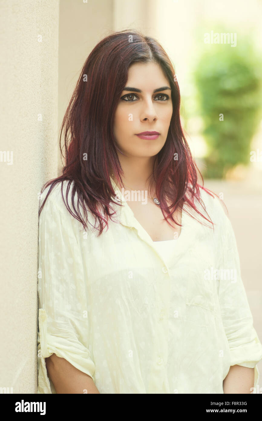 Young woman leaning against the wall looking away outdoors Stock Photo ...