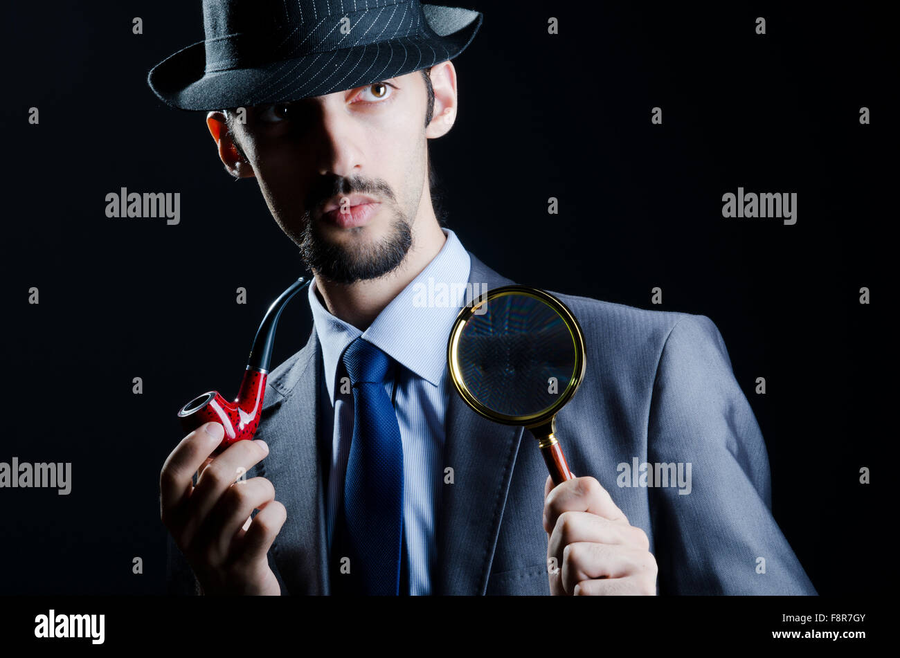 Detective with magnifying glass and pipe Stock Photo - Alamy