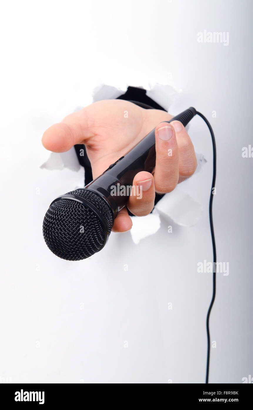 Hand holding microphone through hole in paper Stock Photo - Alamy