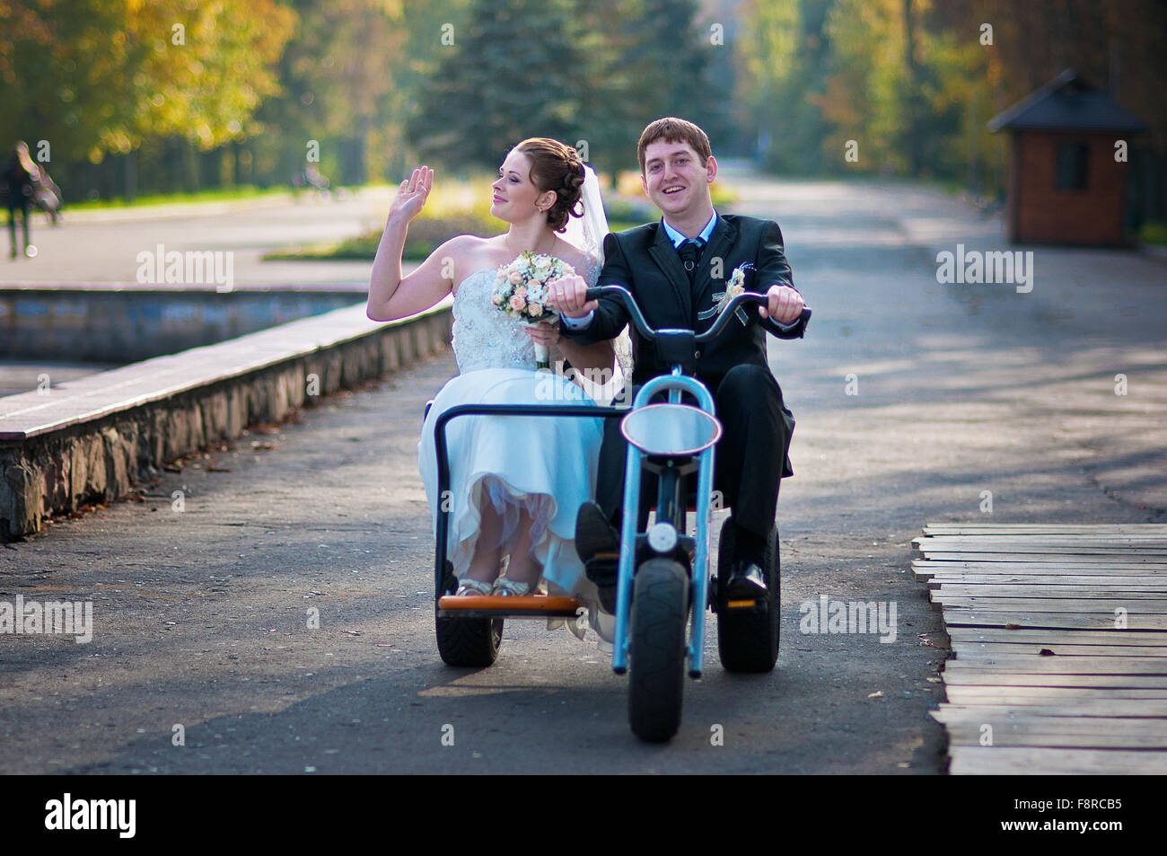 Happy wedding couple on three wheel bike Stock Photo - Alamy