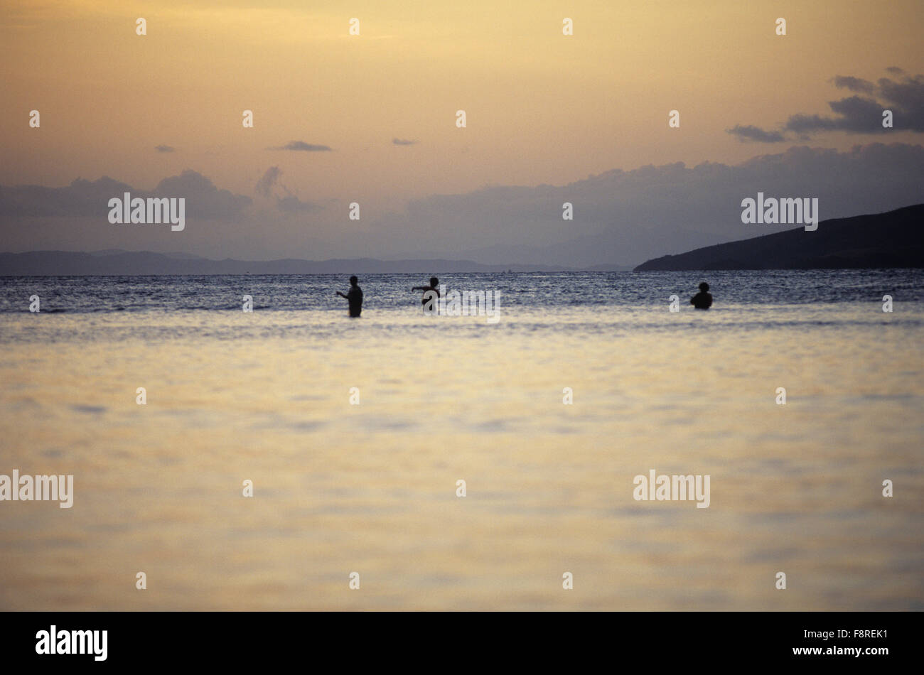 Fijian women hand line fishing on reef at sunset using stones for ...