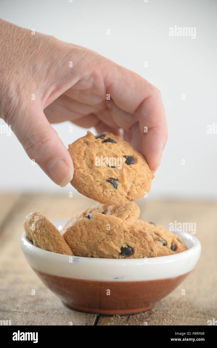 Woman's hand taking a chocolate chip cookie Stock Photo - Alamy