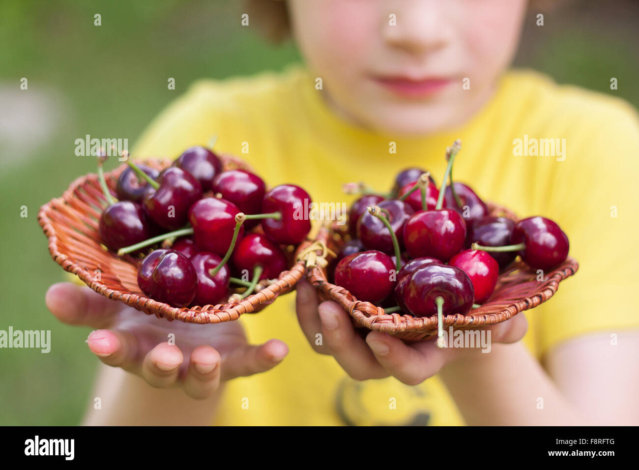 Boy holding two bowls of cherries Stock Photo - Alamy