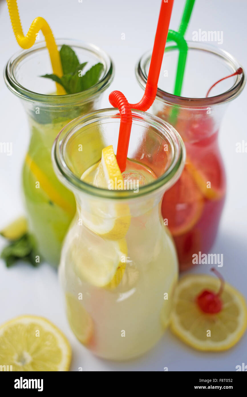 Different tips of lemonade in the jug with straws and lemons on white ...