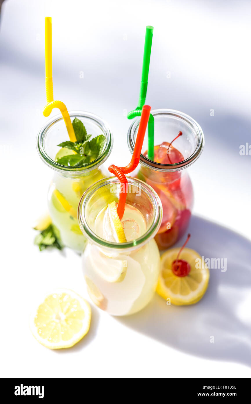 Different tips of lemonade in the jug with straws and lemons on white ...