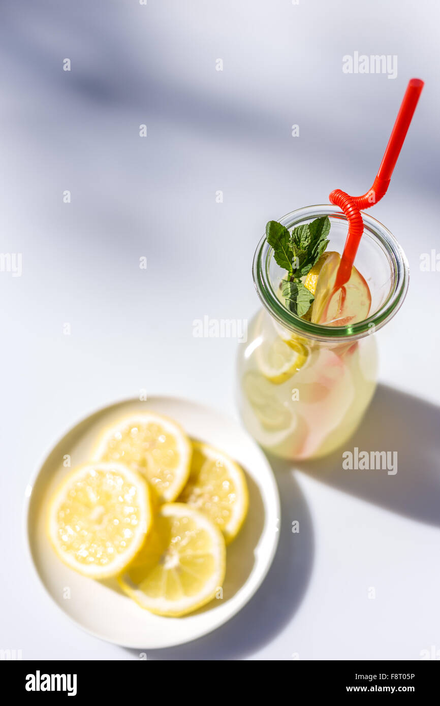 Different tips of lemonade in the jug with straws and lemons on white ...