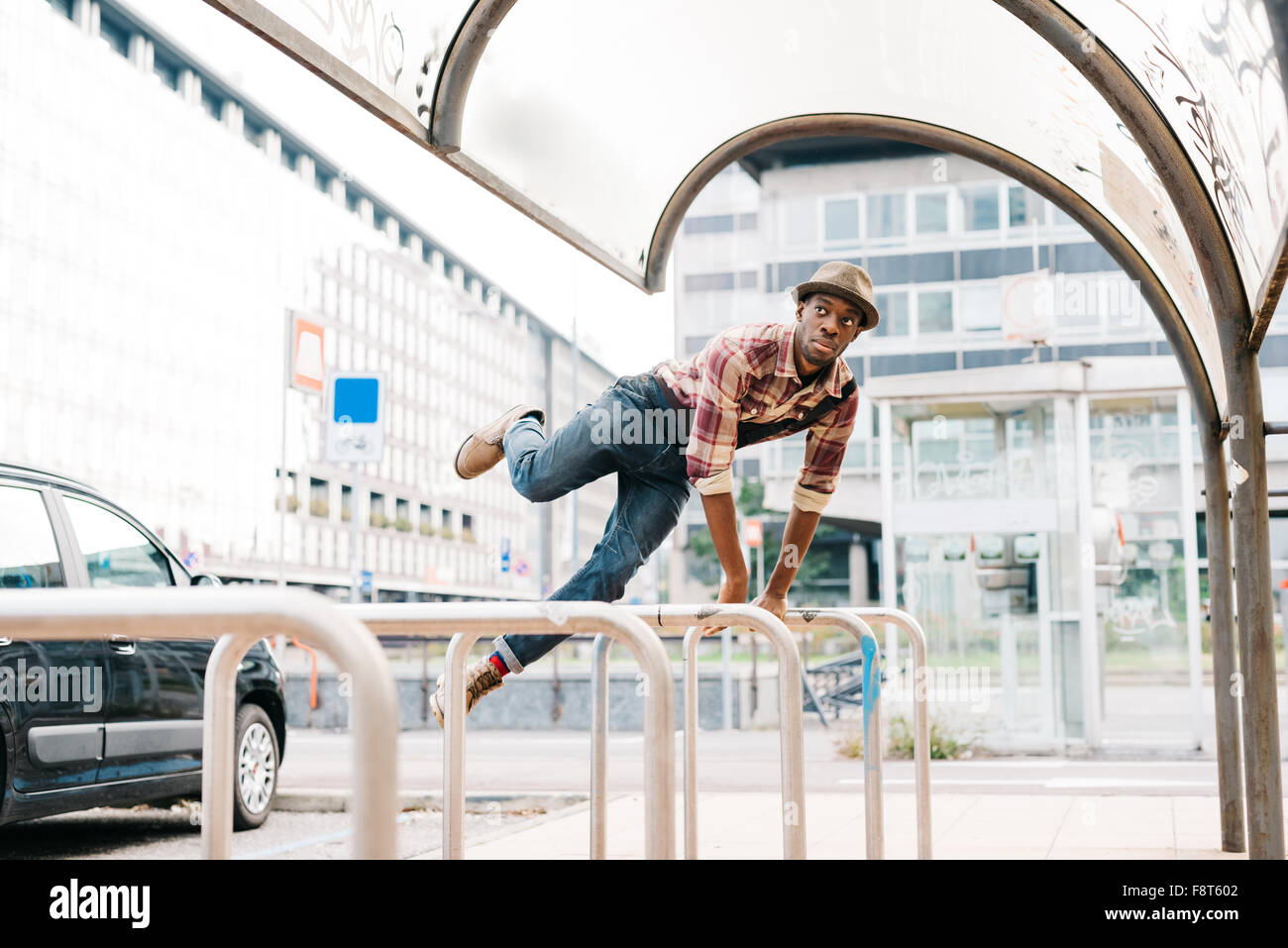 young handsome afro black man jumping leaning his hand on a handrail ...