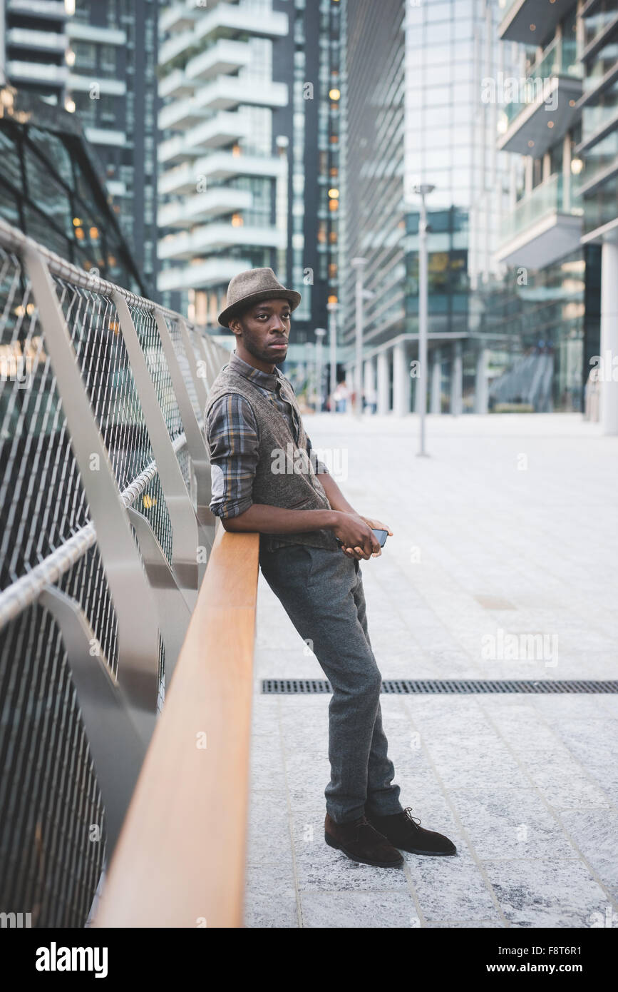 Young handsome afro black man leaning against an handrail wearing gray ...