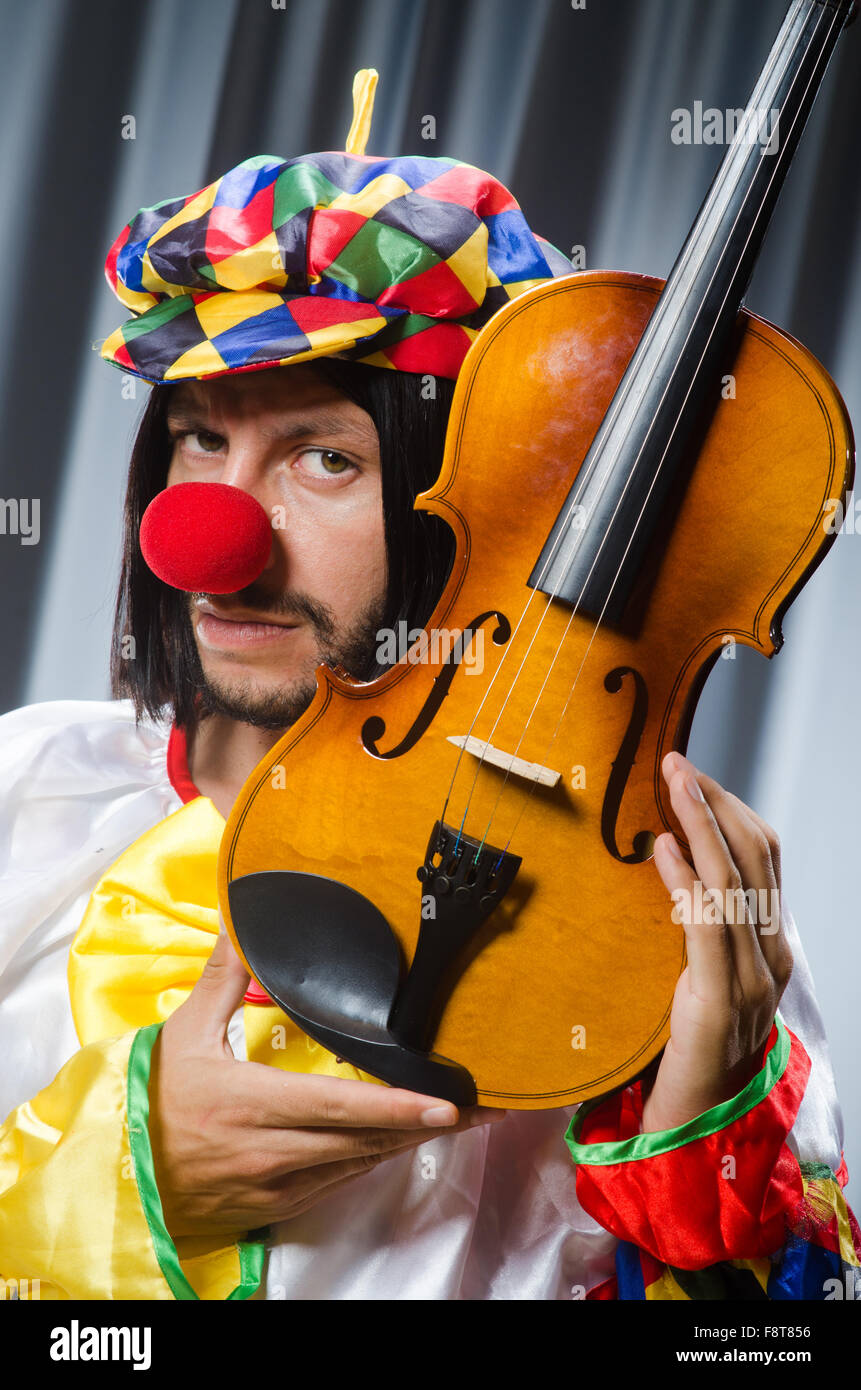 Funny clown plyaing violin against curtain Stock Photo - Alamy