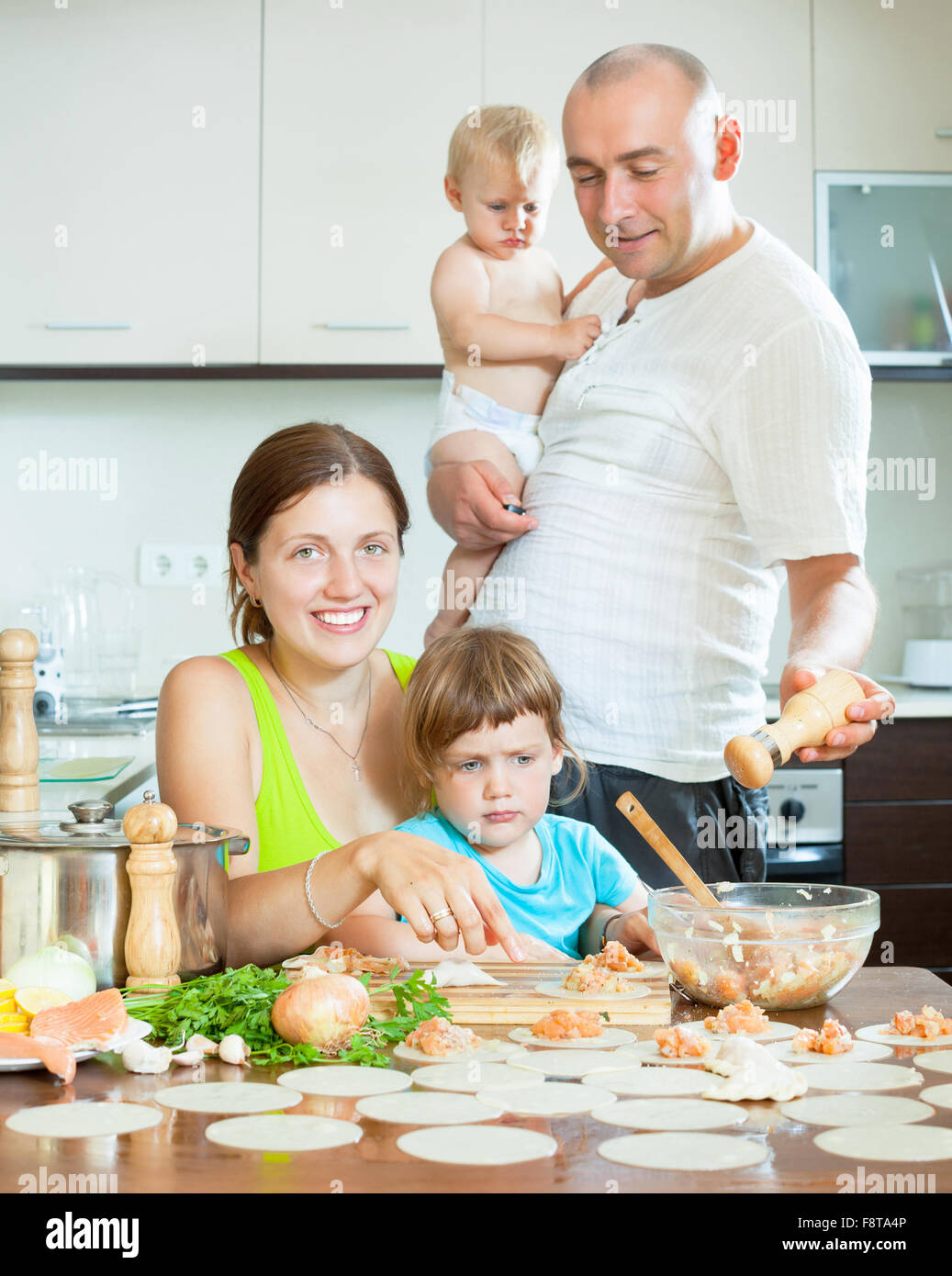 Happy family of four making small dumplings with fish (dumplings) in a ... Happy family of four making small dumplings with fish (dumplings) in a ...