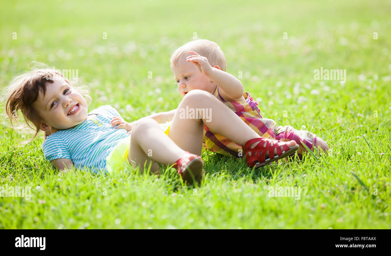 Two happy children playing in grass Stock Photo - Alamy