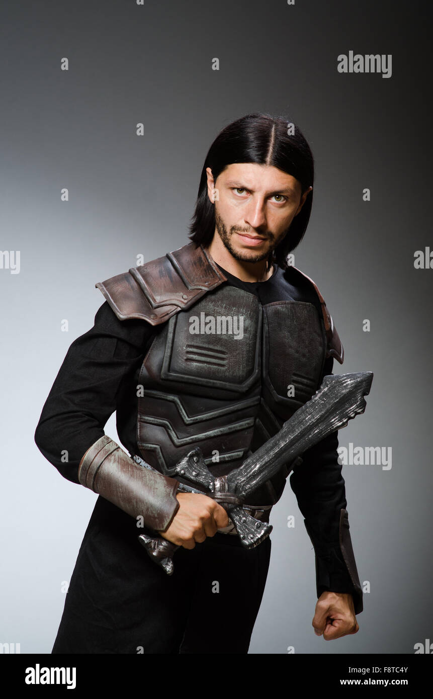 Angry knight with sword against dark background Stock Photo - Alamy