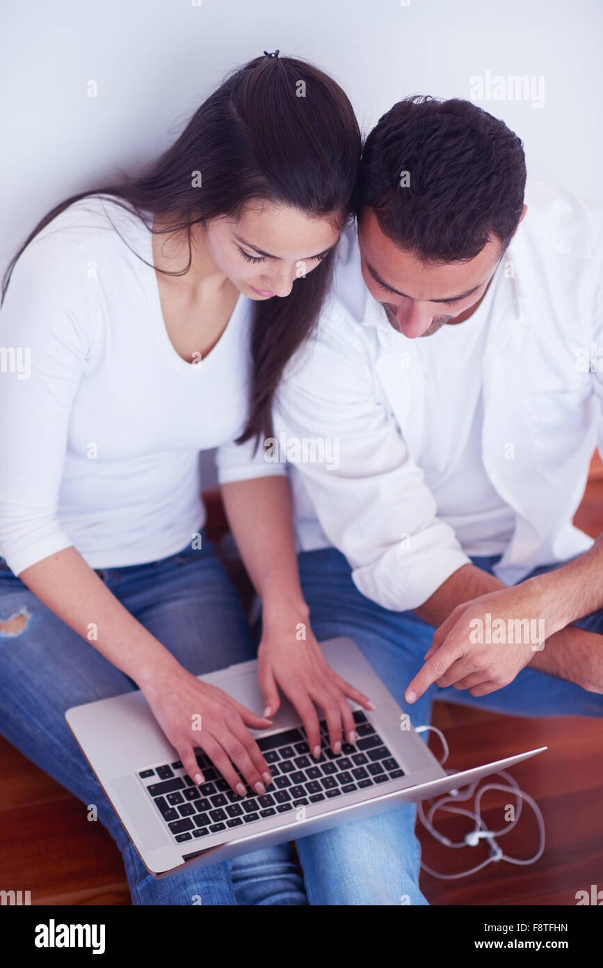 happy young relaxed couple working on laptop computer at modern home ...