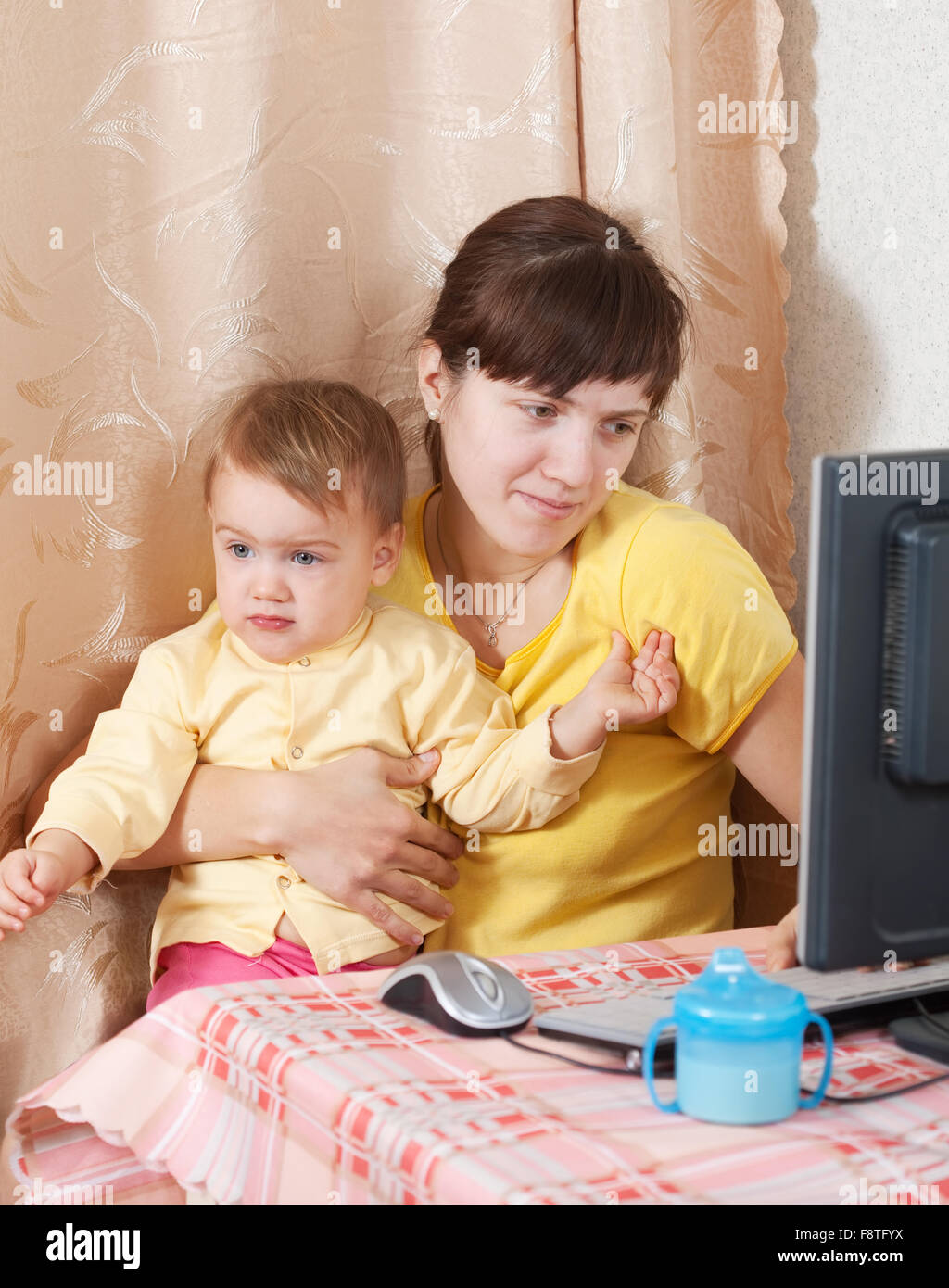 Woman with crying baby working with computer at home Stock Photo - Alamy