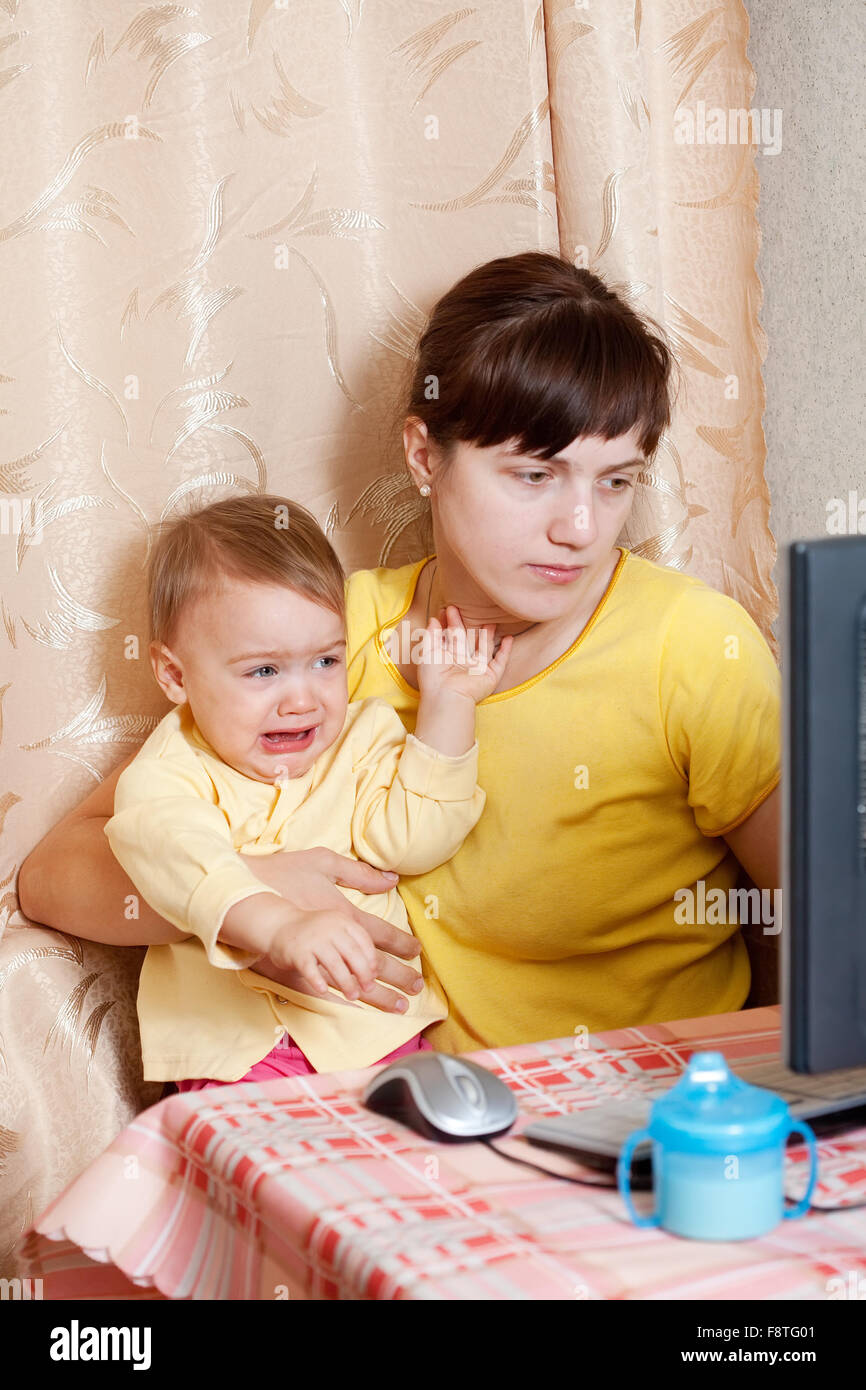 Woman with crying baby working with computer at home Stock Photo - Alamy