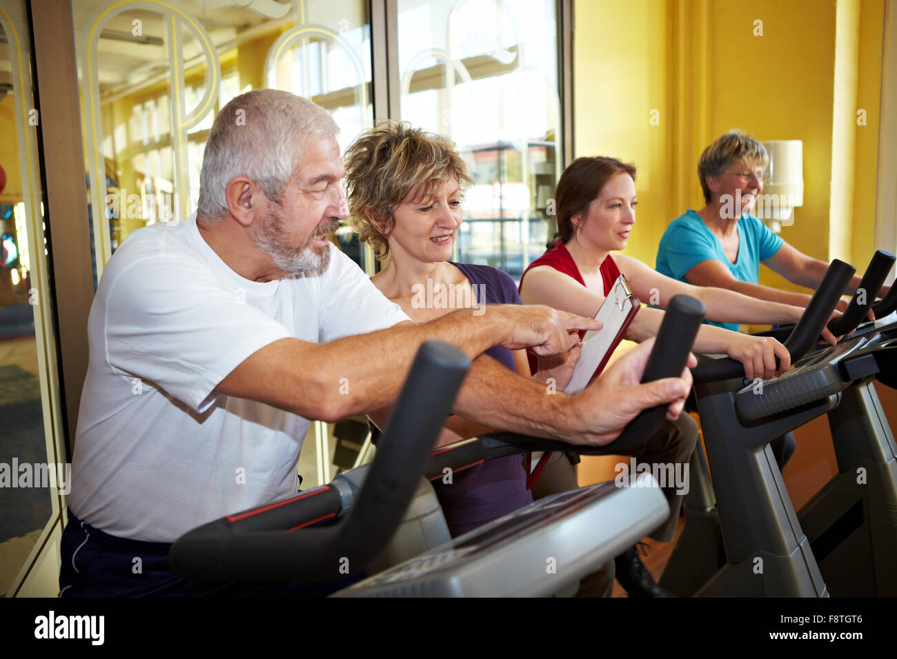 Trainer explaining coaching plan to senior in gym Stock Photo - Alamy