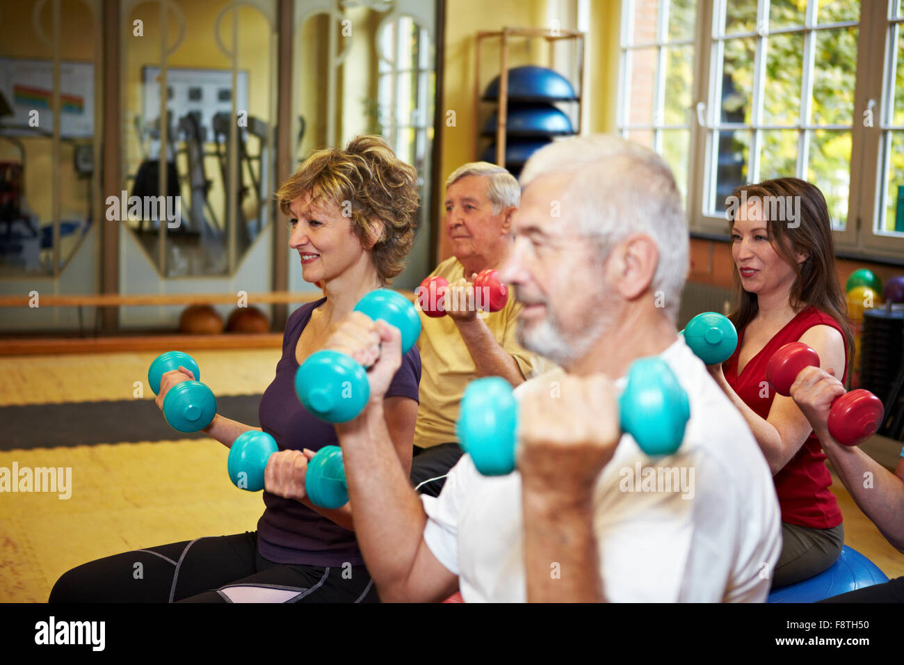 Mixed group doing dumbbell exercises in a gym Stock Photo - Alamy