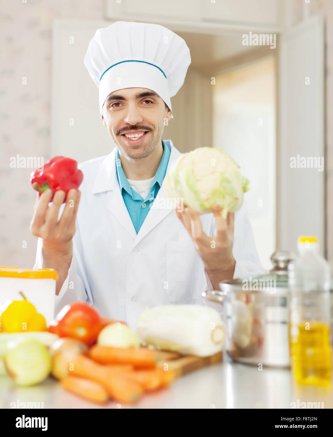 Happy cook man in toque with vegetables in kitchen Stock Photo - Alamy
