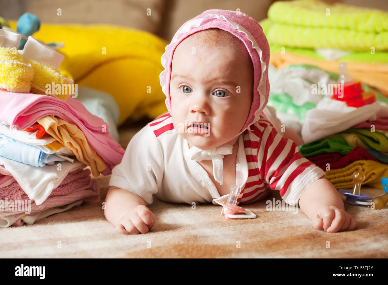 baby girl with stacked of children's clothes Stock Photo - Alamy