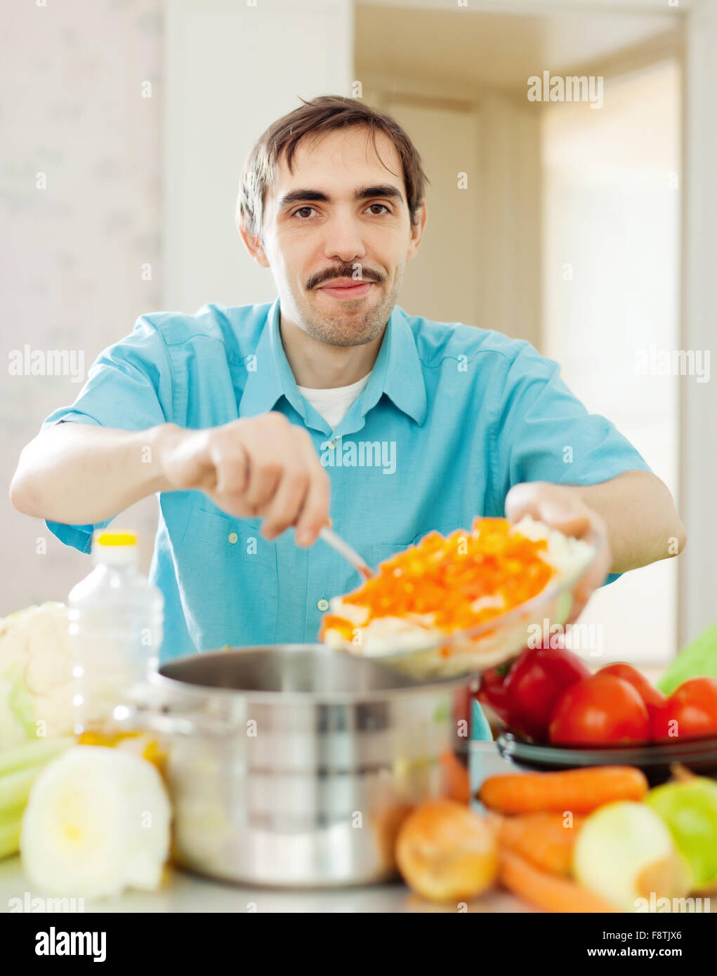 Smiling handsome man cooks lunch with vegetables Stock Photo - Alamy