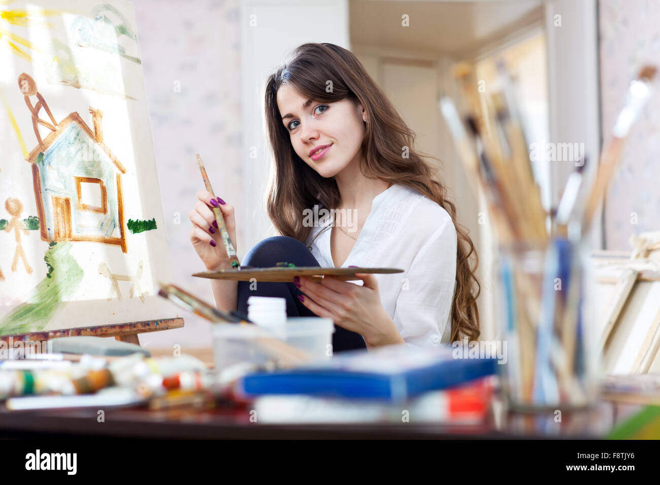 Yuong adult artist paints the house on canvas in workshop Stock Photo ...