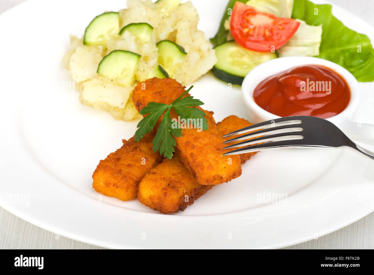 three fish fingers and potatoe salad Stock Photo - Alamy