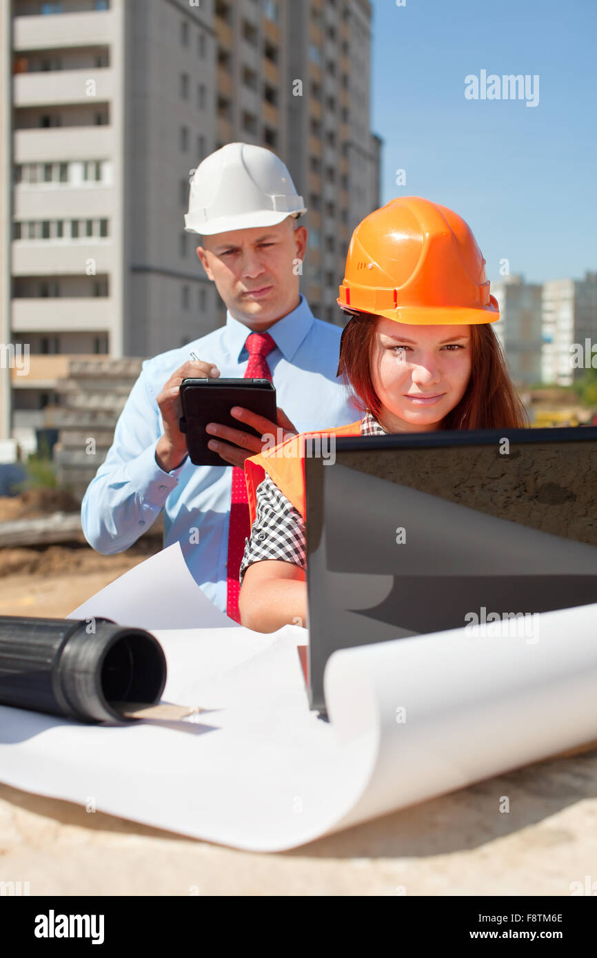 Two architects wearing protective helmet works in front of building ...