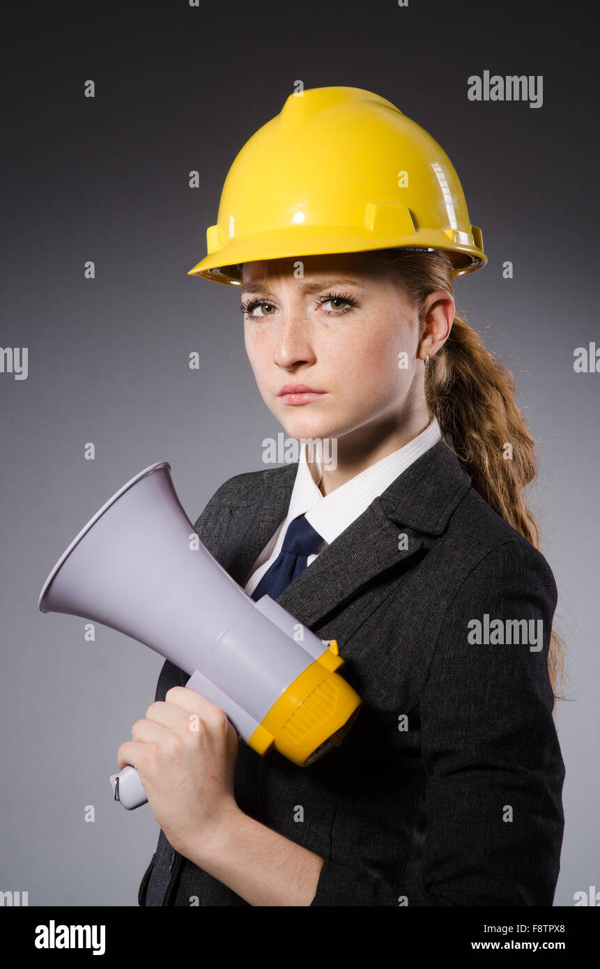 Female engineer with helmet and loudspeaker isolated on gray Stock ...