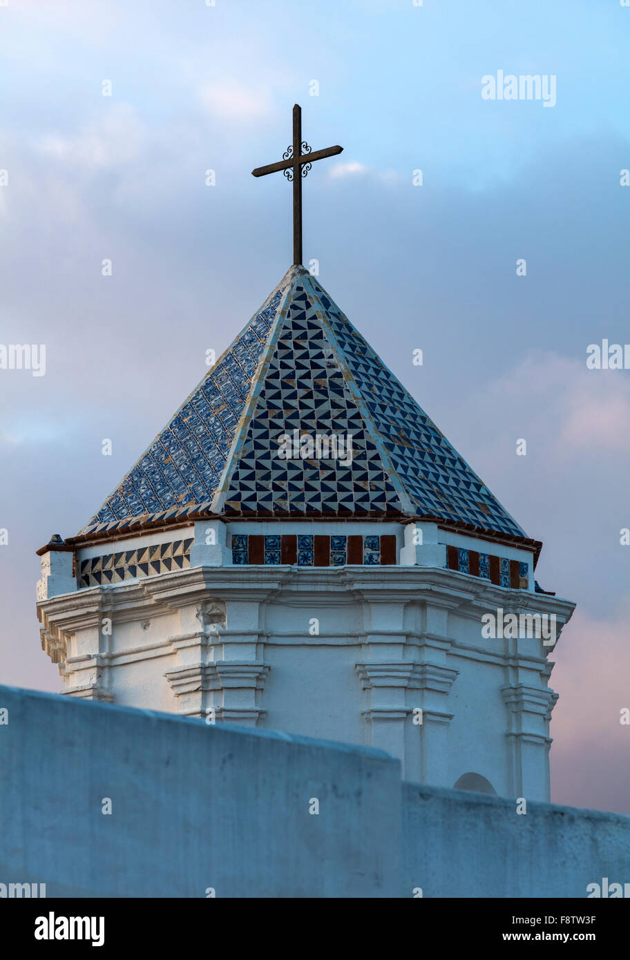 Close up of a church tower with crucifix with a tiled roof and dramatic ...