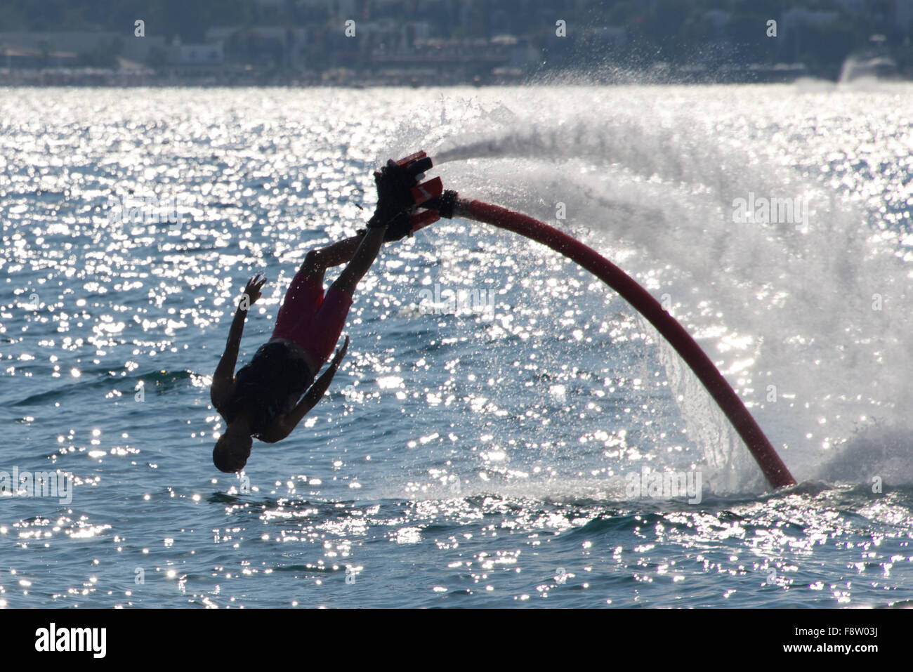 Flyboarder diving backwards headfirst into backlit sea Stock Photo - Alamy