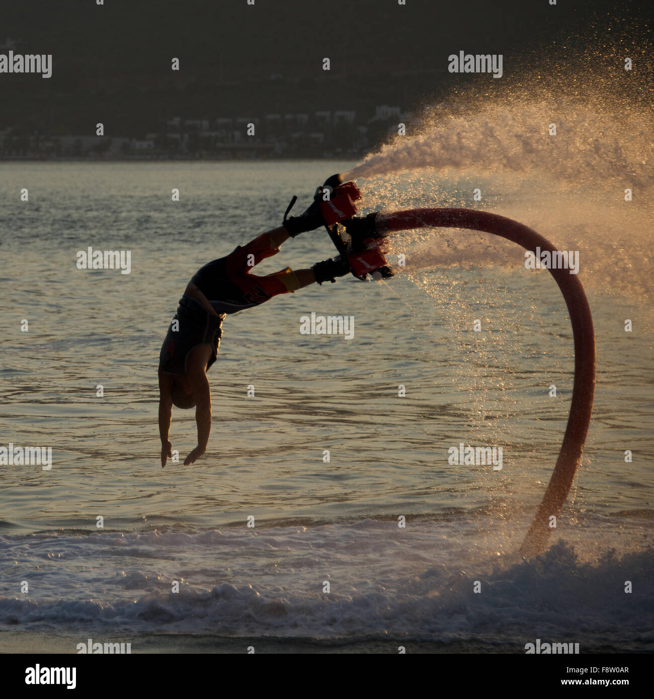 Flyboarder diving followed by backlit water jet Stock Photo - Alamy