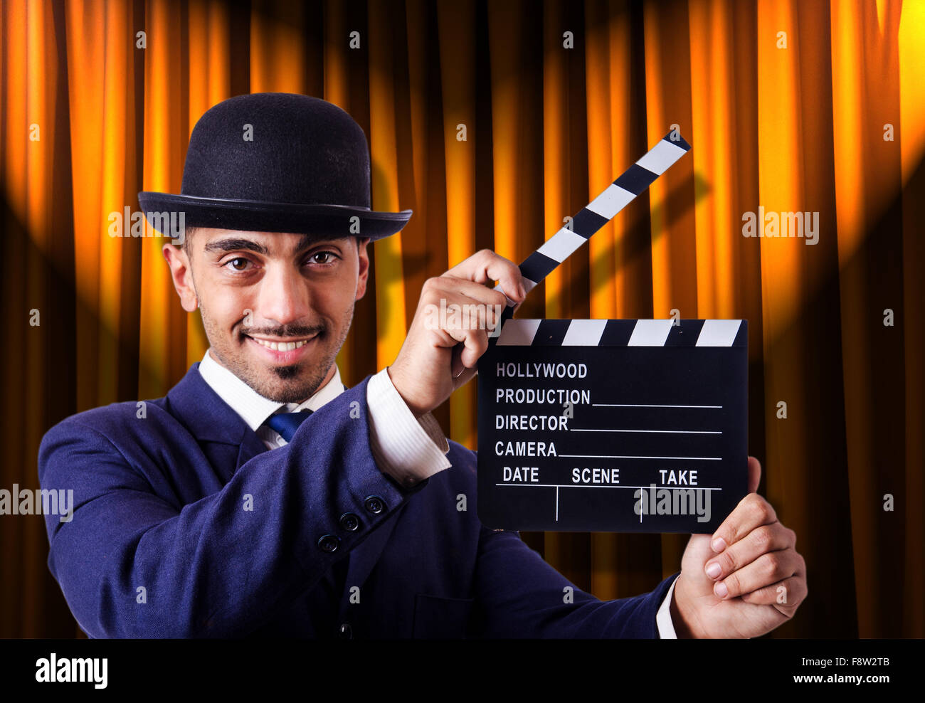 Man with movie clapper on curtain background Stock Photo - Alamy