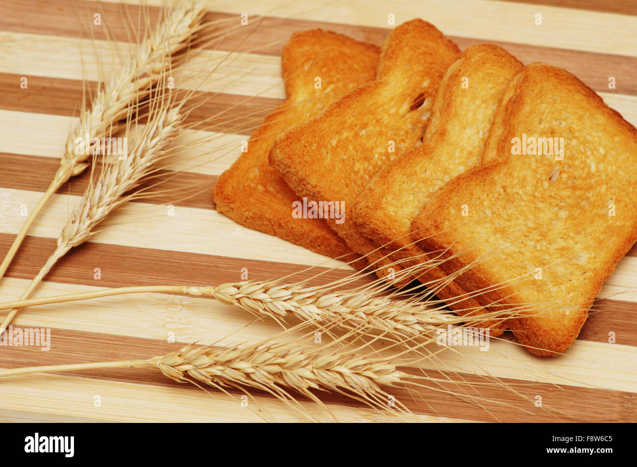Four toast pieces and wheat ears on wooden board Stock Photo - Alamy